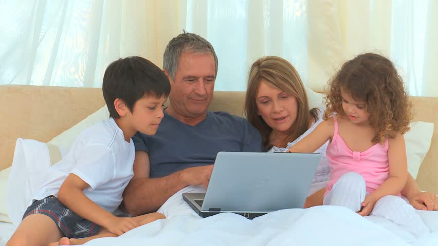 Parents Using Laptop And Children Colouring At The Table At Home In ...