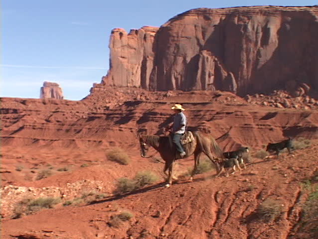 A Cowboy On Horseback Rides Through In Monument Valley, Utah. Stock ...