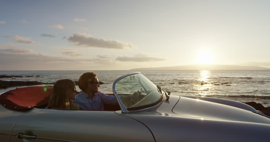 Happy Couple Driving Into Sunset In Classic Vintage Sports Car By The ...