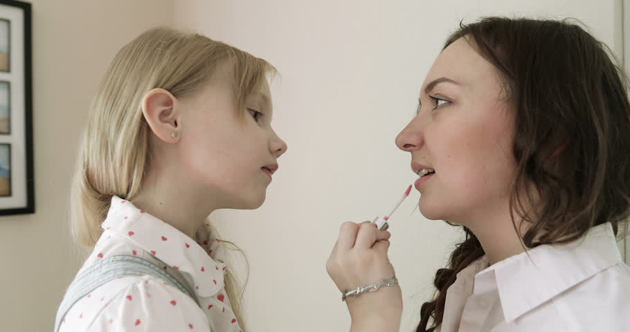 Mother Makes Up Lips With Lipstick To The Daughter And Kisses It, Close ...