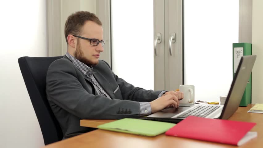 Young, Handsome Man Sitting Behind The Desk And In Using Computer, Then ...
